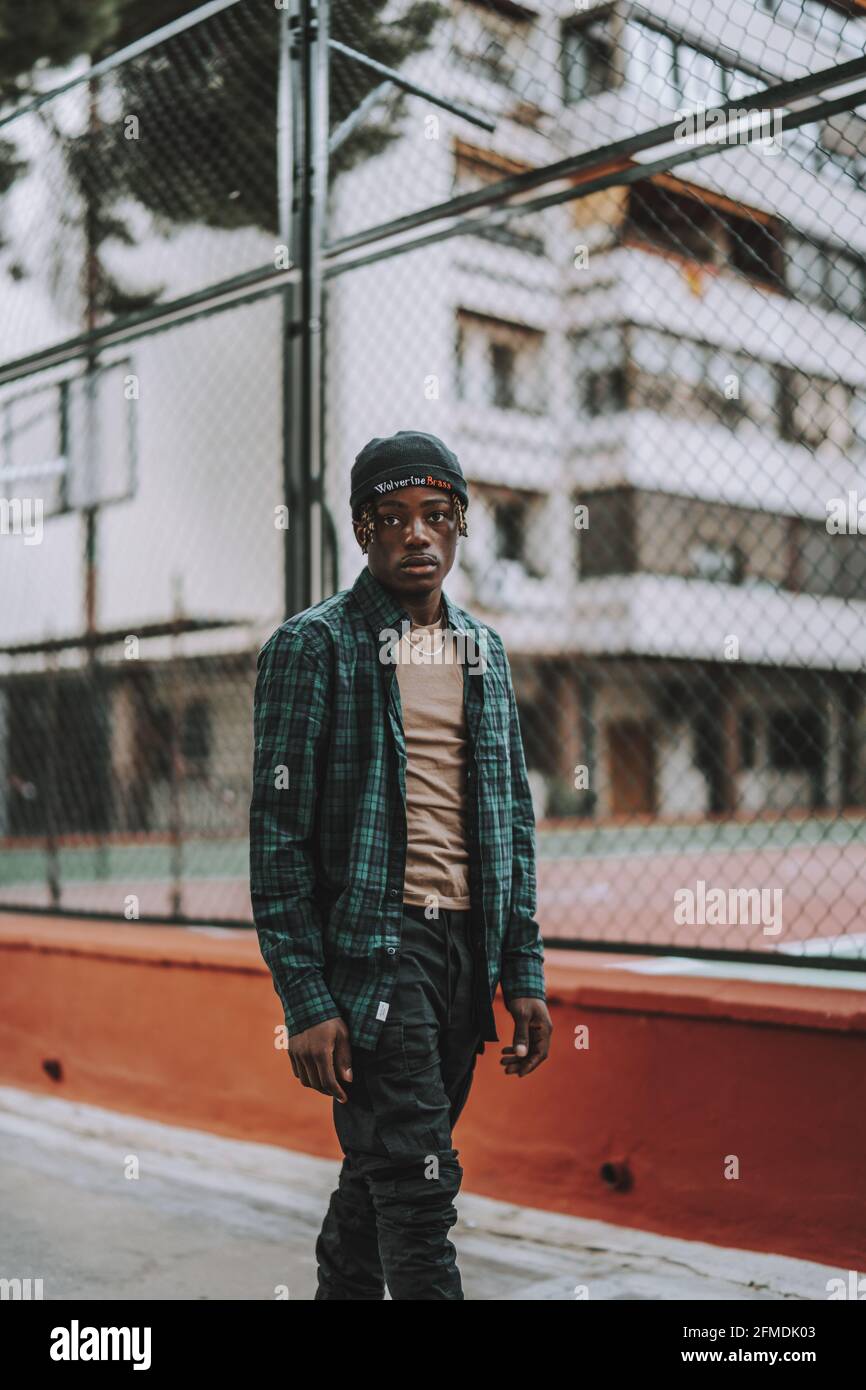 Handsome and stylish Spanish man posing with a chain-link fence on the ...