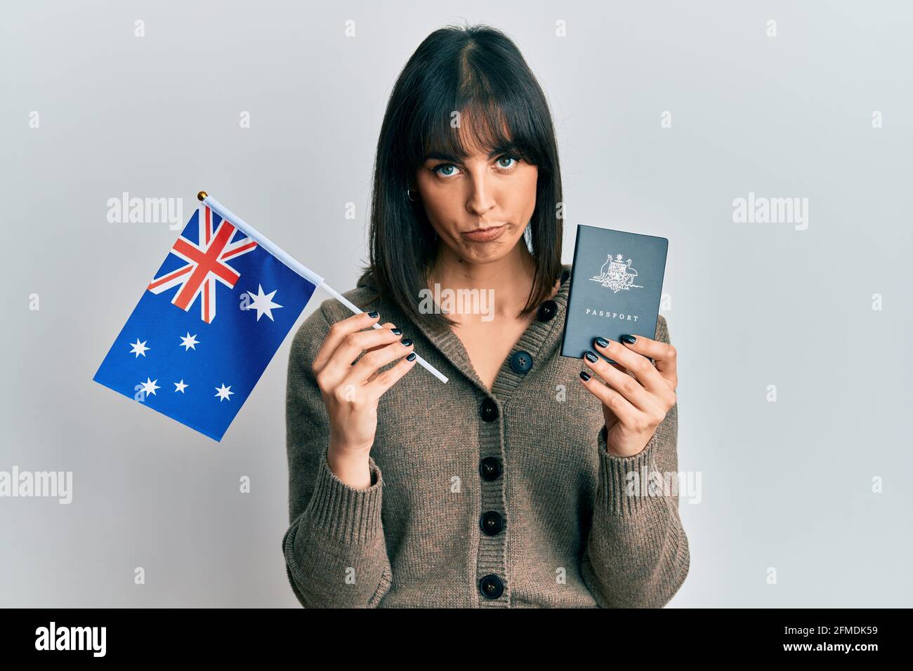 Young hispanic woman holding australian flag and passport depressed and ...