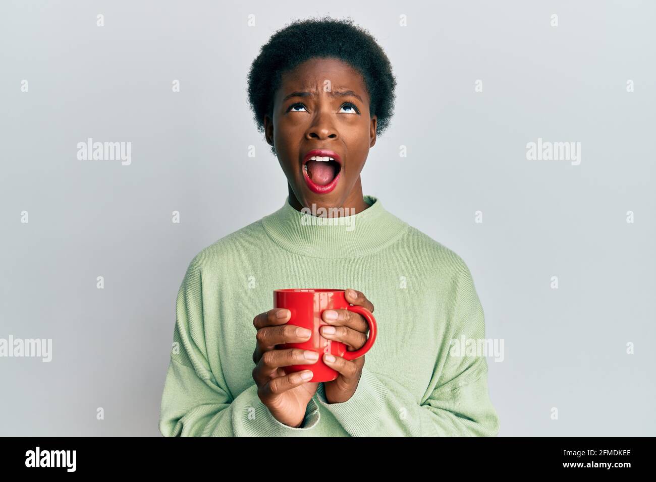 Young african american girl drinking a cup of coffee angry and mad ...
