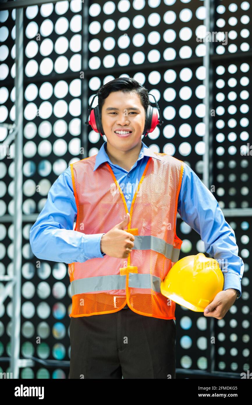 Asian Indonesian construction worker with helmet and safety vest on a ...