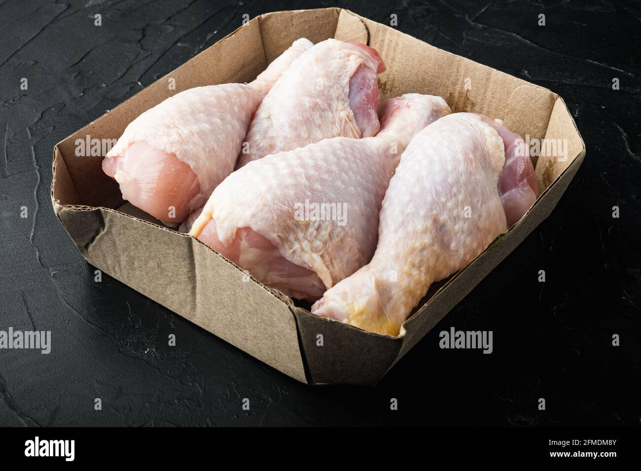 Fresh Chicken Whole Legs set, in paper Pack, on black stone background ...