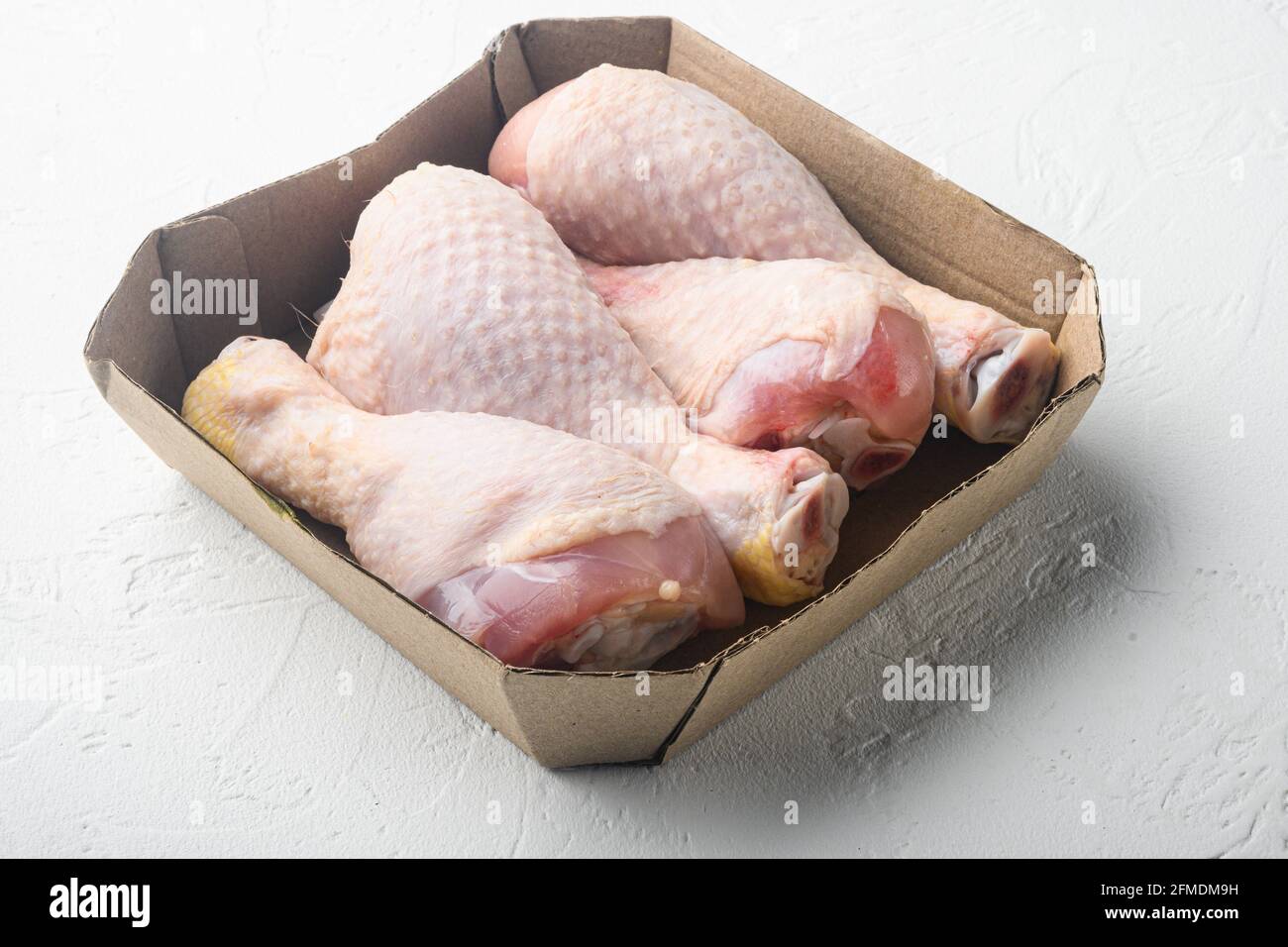 Family pack of fresh chicken legs set, in paper Pack, on white stone ...