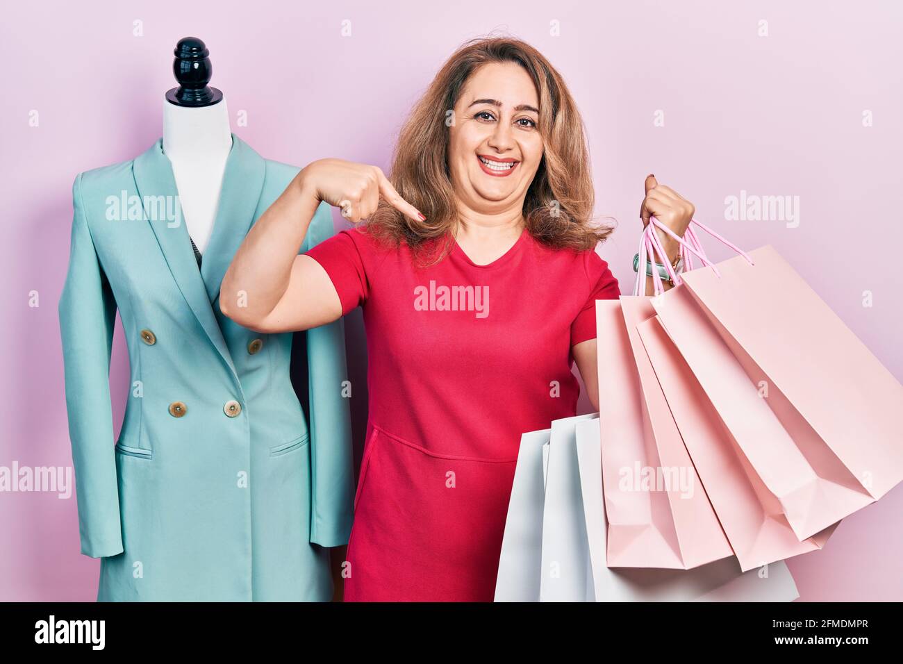 Middle age caucasian woman holding shopping bags pointing finger to one ...