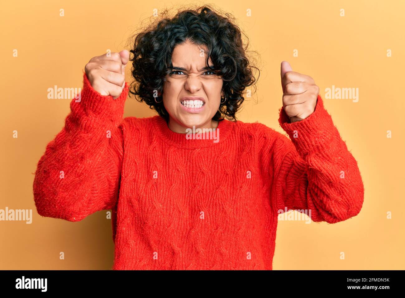 Young hispanic woman with curly hair wearing casual winter sweater ...