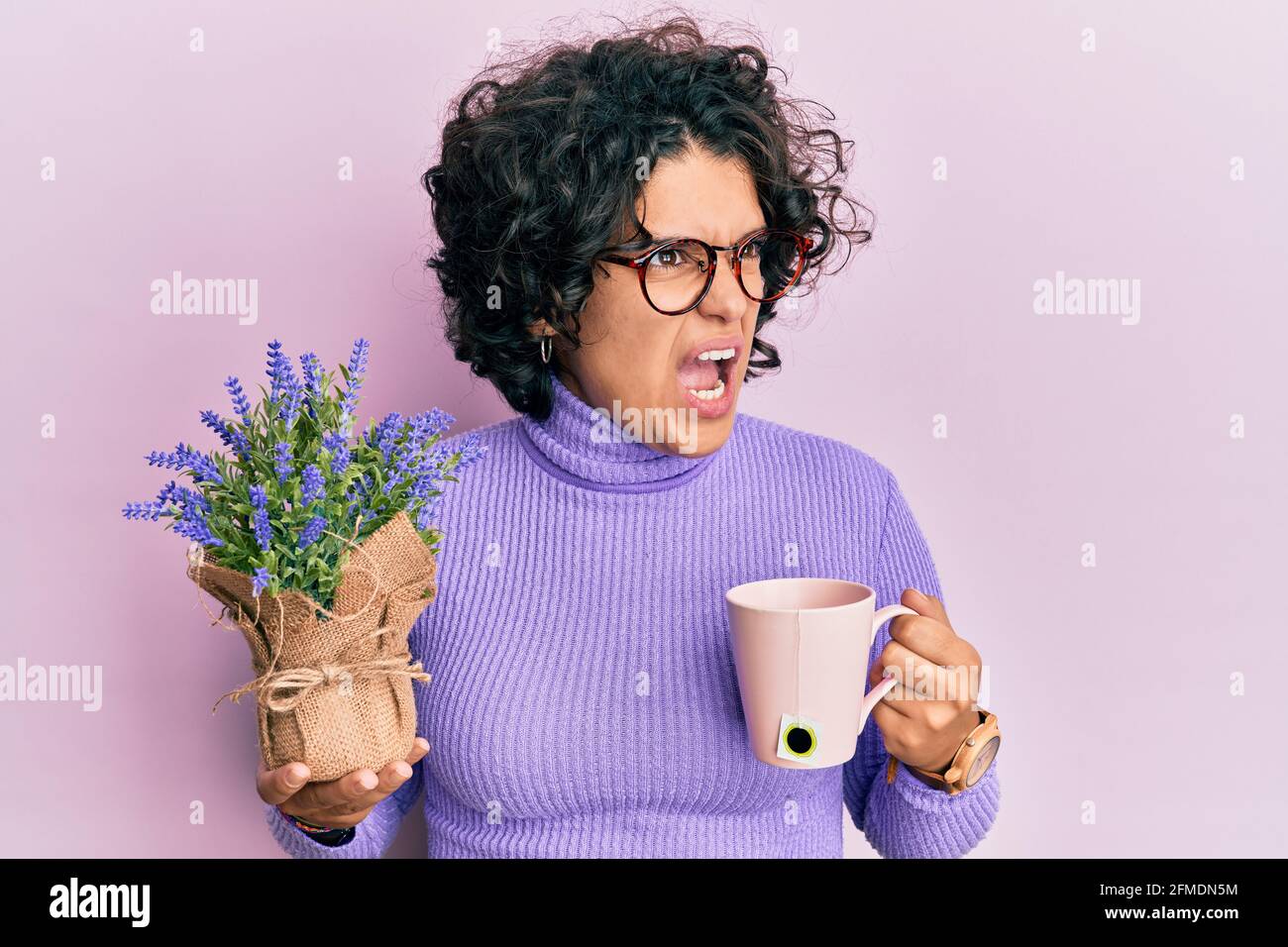 Young hispanic woman with curly hair drinking a cup of infused lavender ...