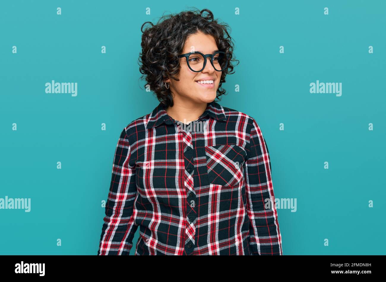 Young hispanic woman with curly hair wearing casual clothes and glasses ...