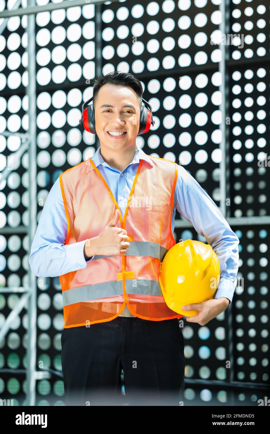 Asian Indonesian construction worker with helmet and safety vest on a ...
