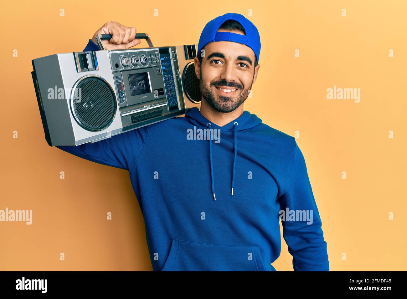 Young hispanic man holding boombox, listening to music looking positive ...