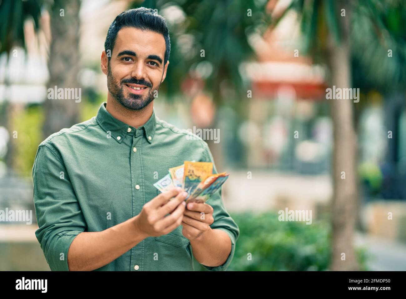 Young hispanic man smiling happy counting australian dollars at the ...