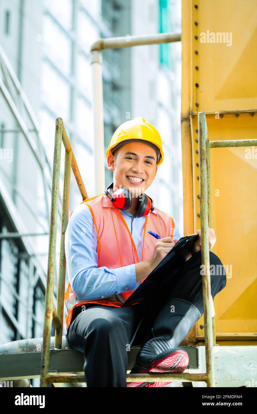 Asian Indonesian construction worker with helmet and safety vest on a ...