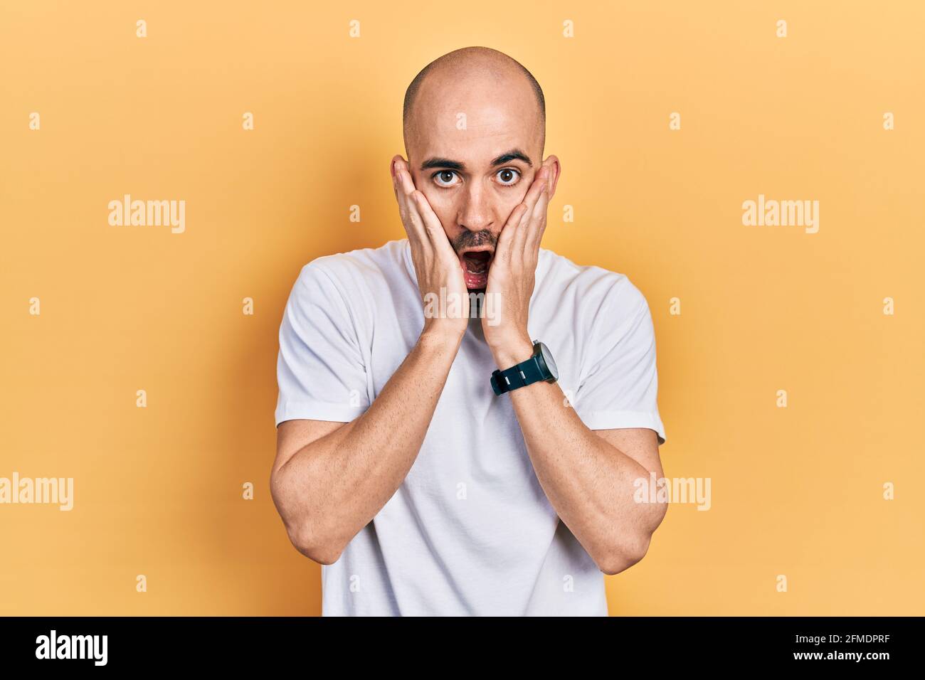 Young bald man wearing casual white t shirt afraid and shocked ...