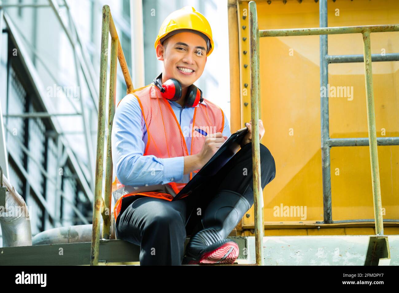 Asian Indonesian construction worker with helmet and safety vest on a ...