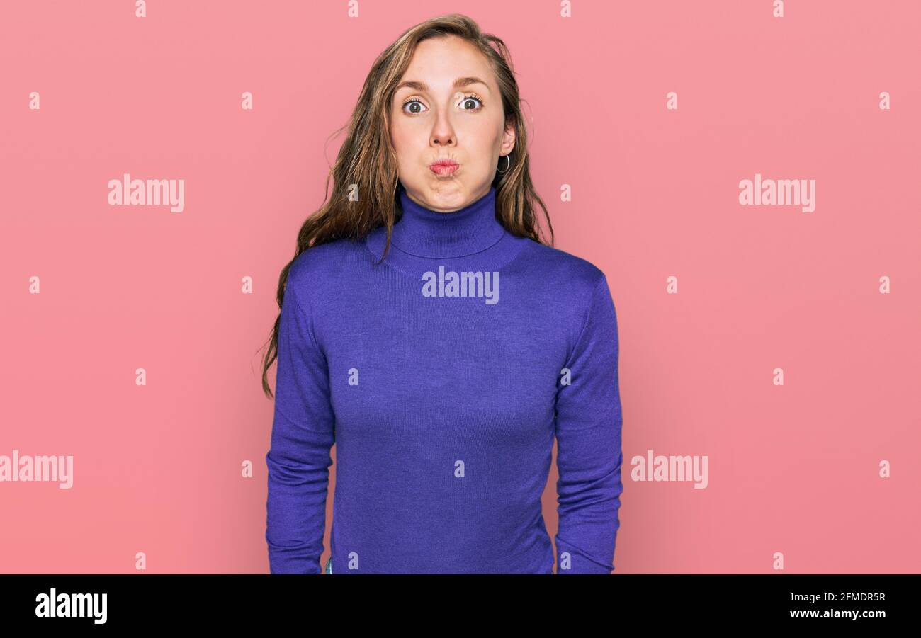 Young blonde woman wearing casual clothes puffing cheeks with funny ...