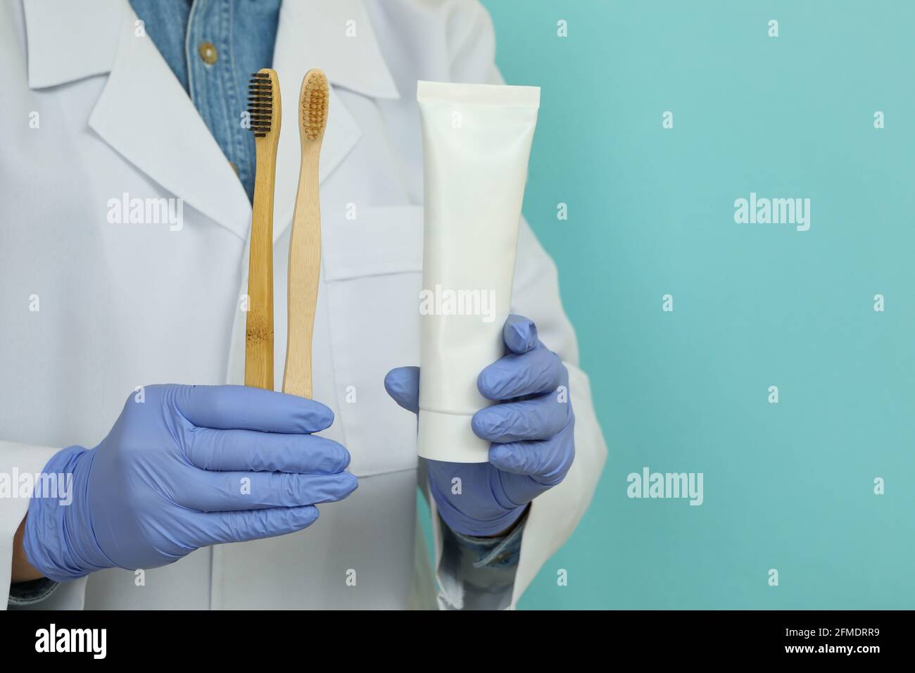 Doctor hold toothpaste and toothbrushes on blue background Stock Photo ...