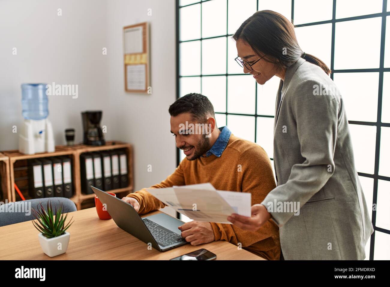 Two business workers smiling happy working sitting on desk at the ...