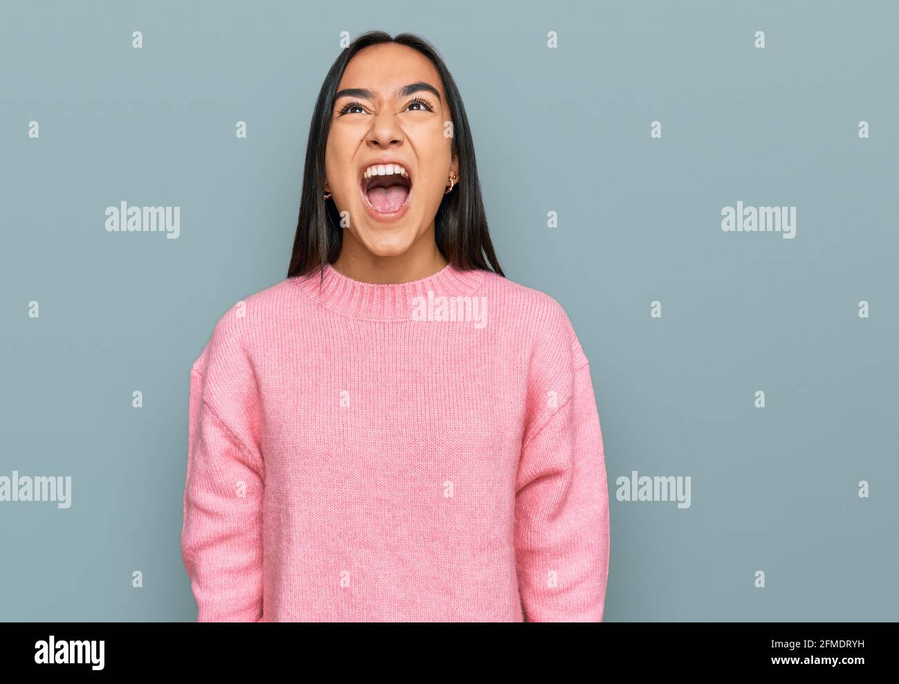 Young asian woman wearing casual winter sweater angry and mad screaming ...