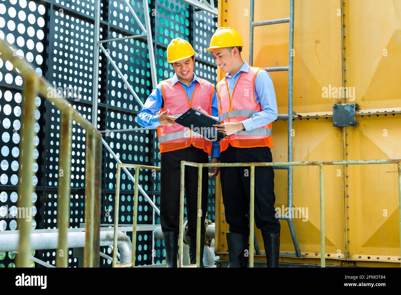 Asian Indonesian construction workers with helmet and safety vest on a ...