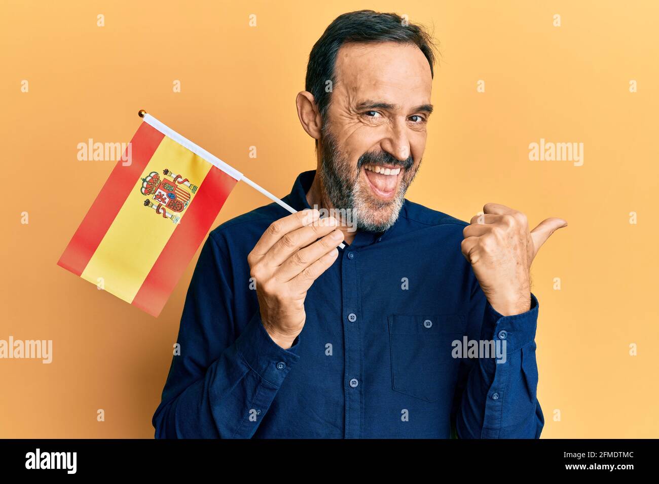Middle age hispanic man holding spain flag pointing thumb up to the ...