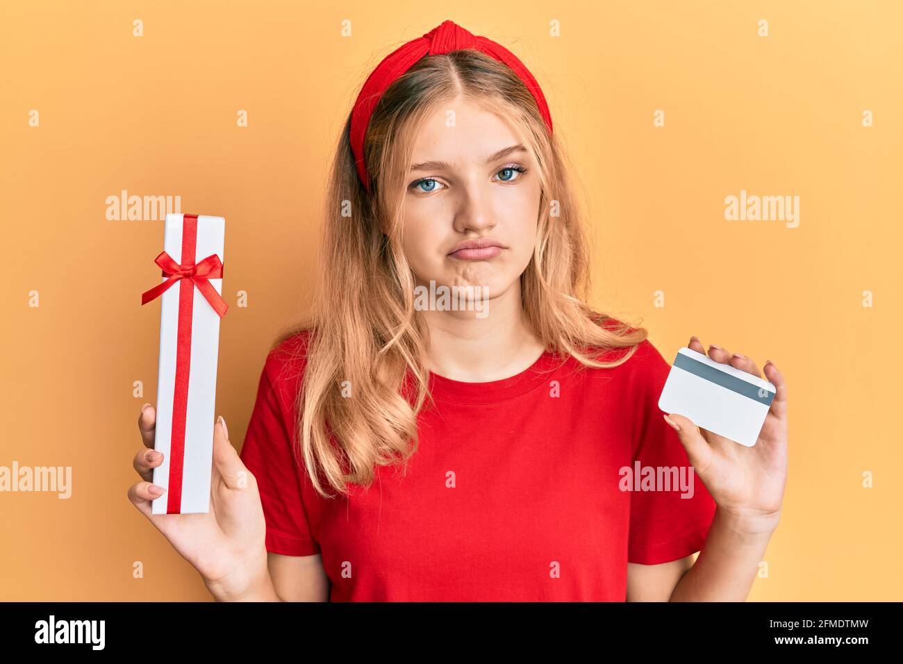 Beautiful young caucasian girl holding gift and credit card depressed ...