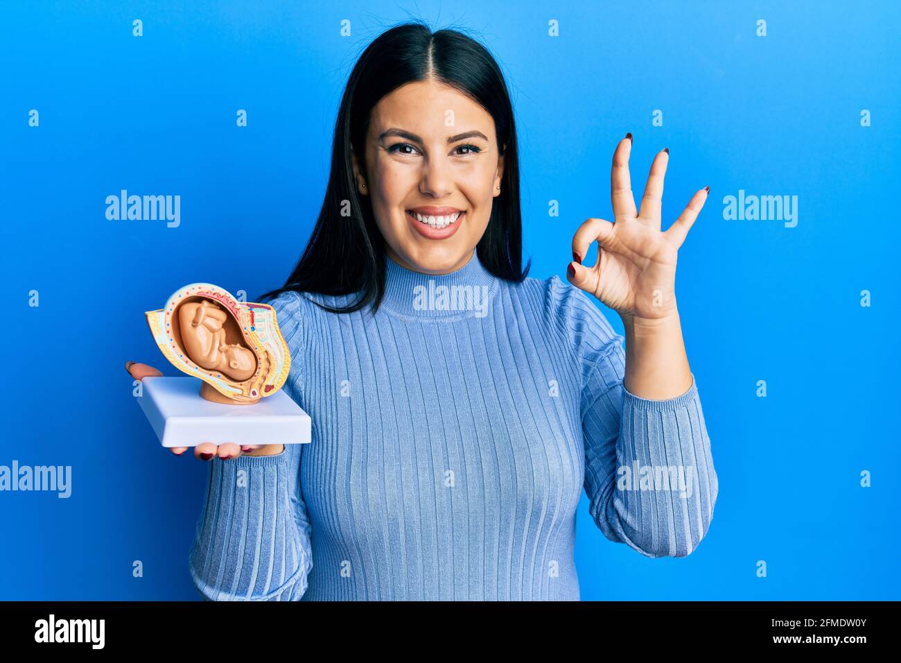 Beautiful brunette woman holding anatomical model of female uterus with ...