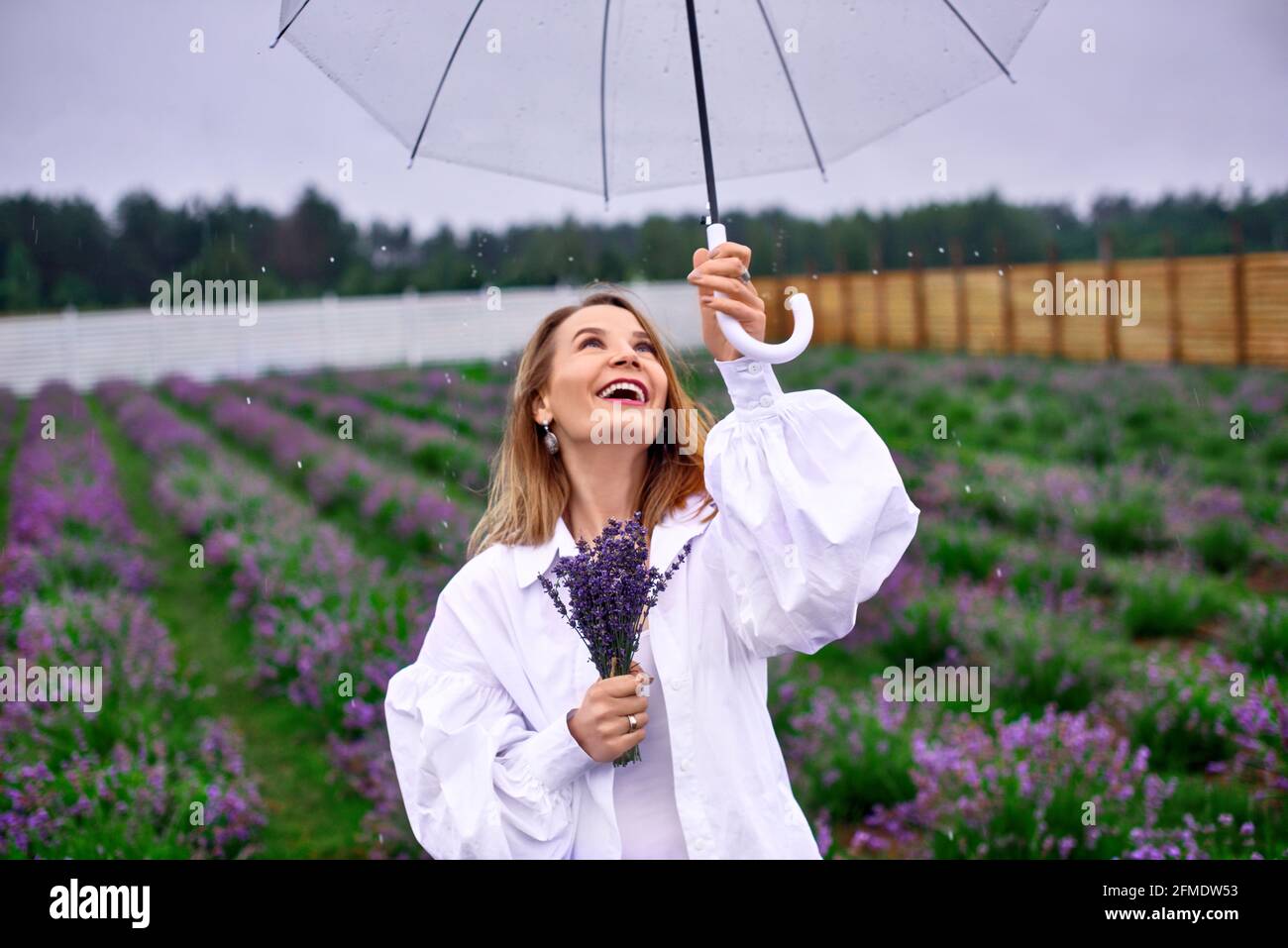 happy woman dancing under rain, holding umbrella and bouquet and ...