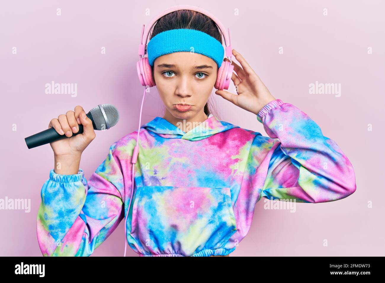 Young brunette girl singing song using microphone wearing sportswear ...