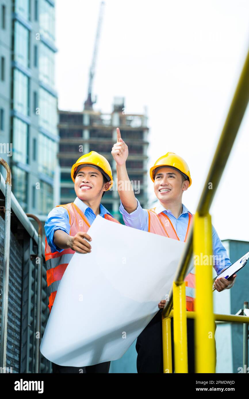 Asian Indonesian construction workers with blueprint or plan on ...