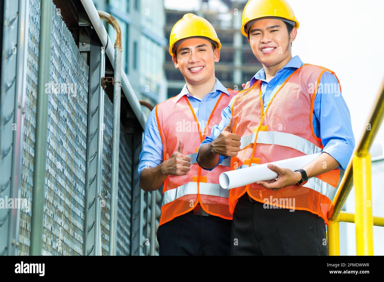Asian Indonesian construction workers with blueprint or plan on ...