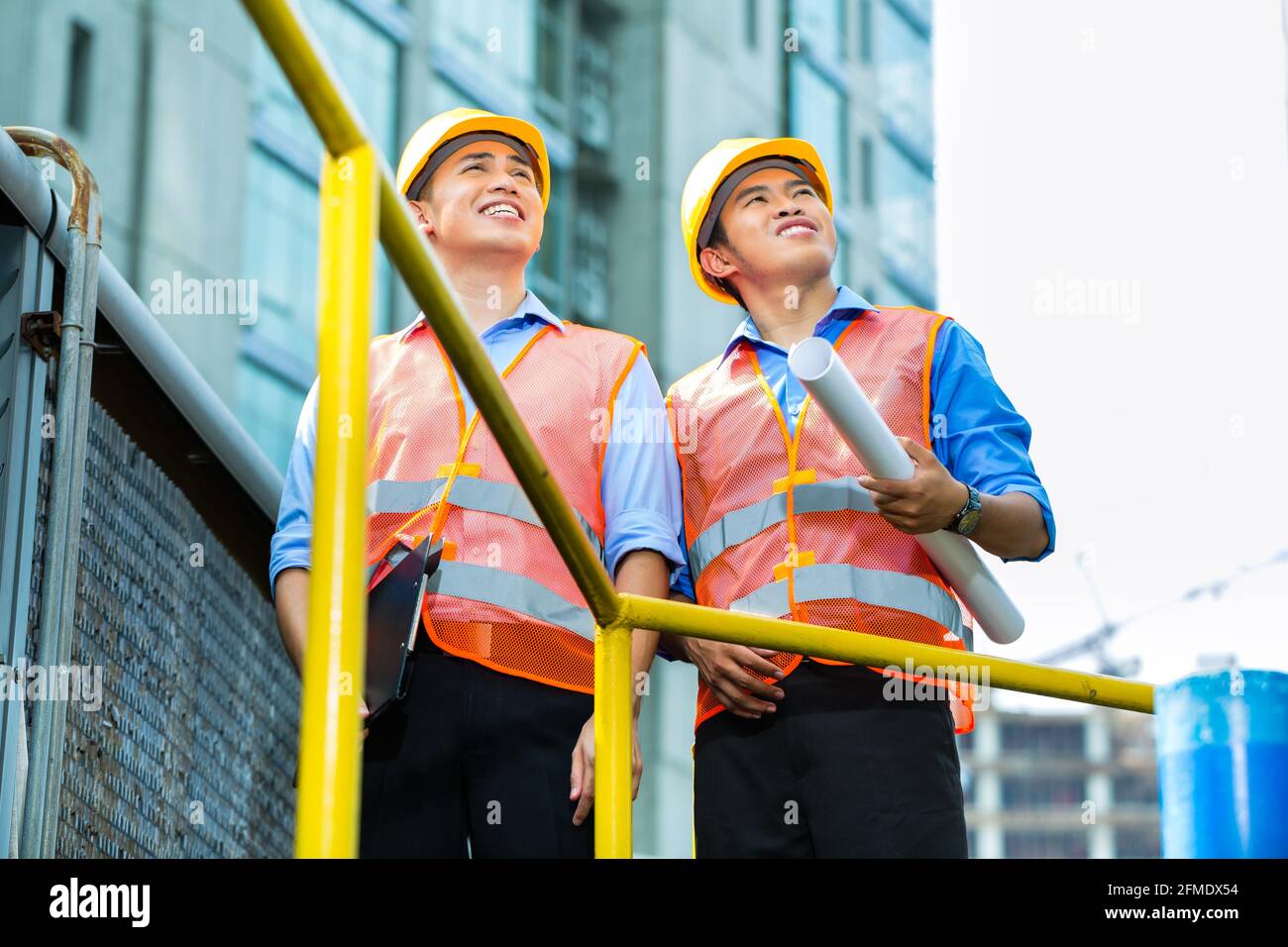 Asian Indonesian construction workers with blueprint or plan on ...