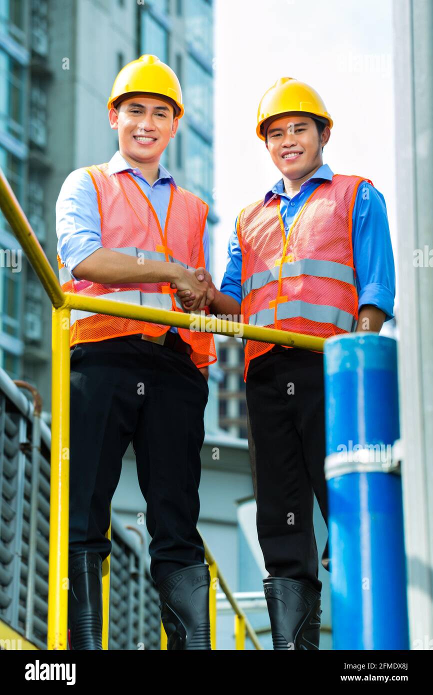 Asian Indonesian construction workers with blueprint or plan on ...