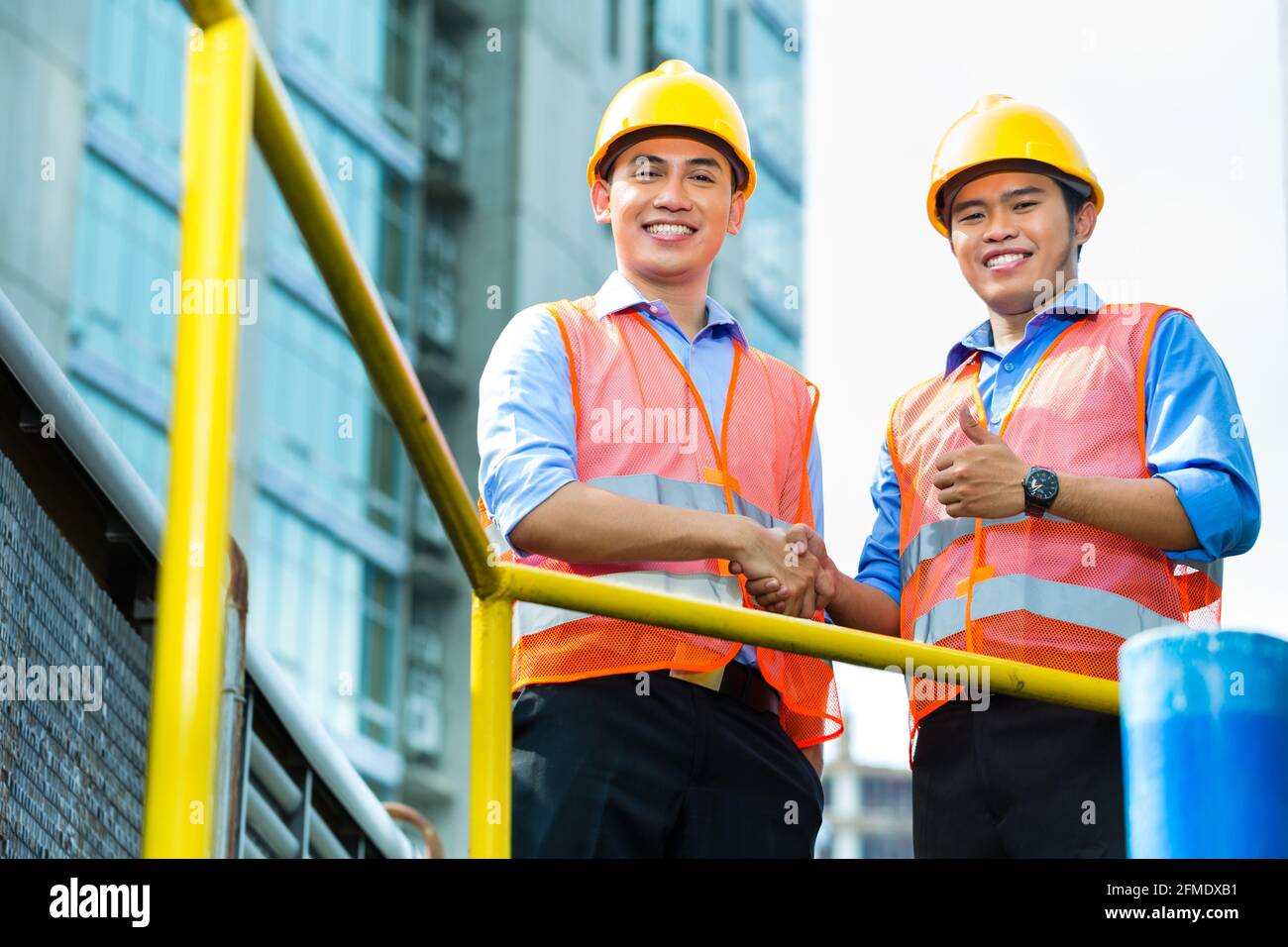 Asian Indonesian construction workers with blueprint or plan on ...