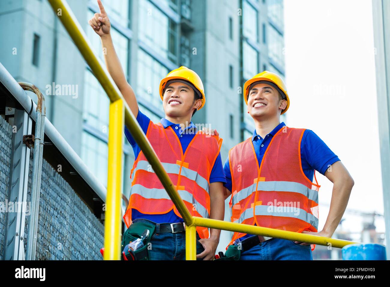 Asian Indonesian construction workers with helmet and safety vest on a ...