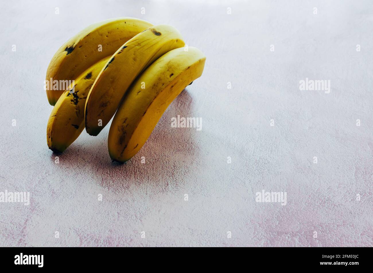 Cluster of bananas on pink textured background Stock Photo - Alamy