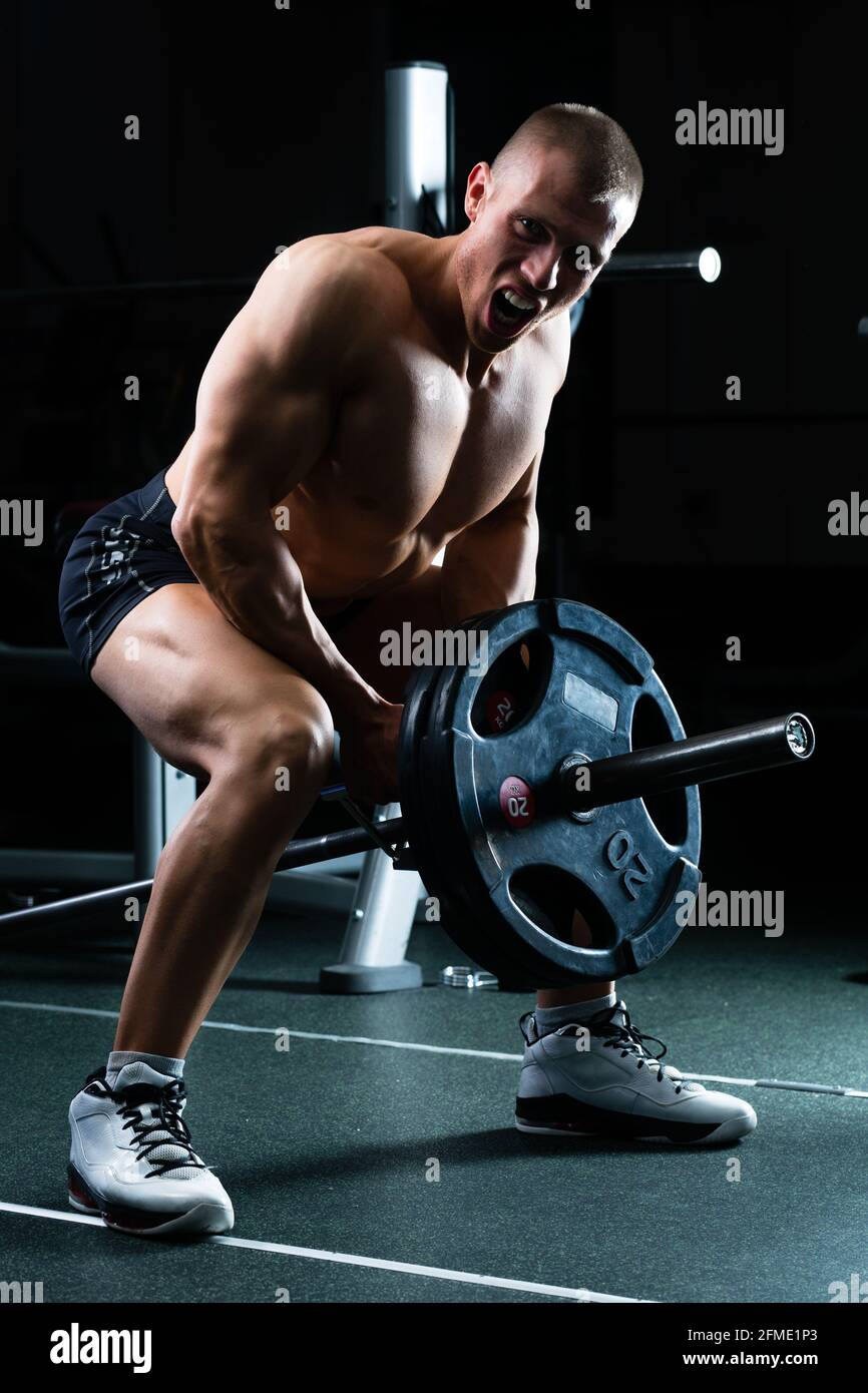 Strong man - bodybuilder with dumbbells in a gym, exercising with a ...