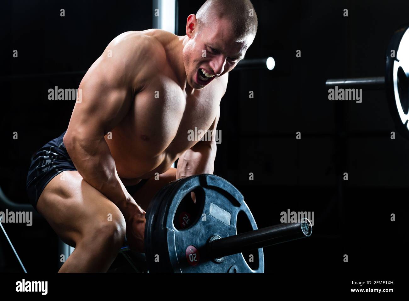 Strong man - bodybuilder with dumbbells in a gym, exercising with a ...