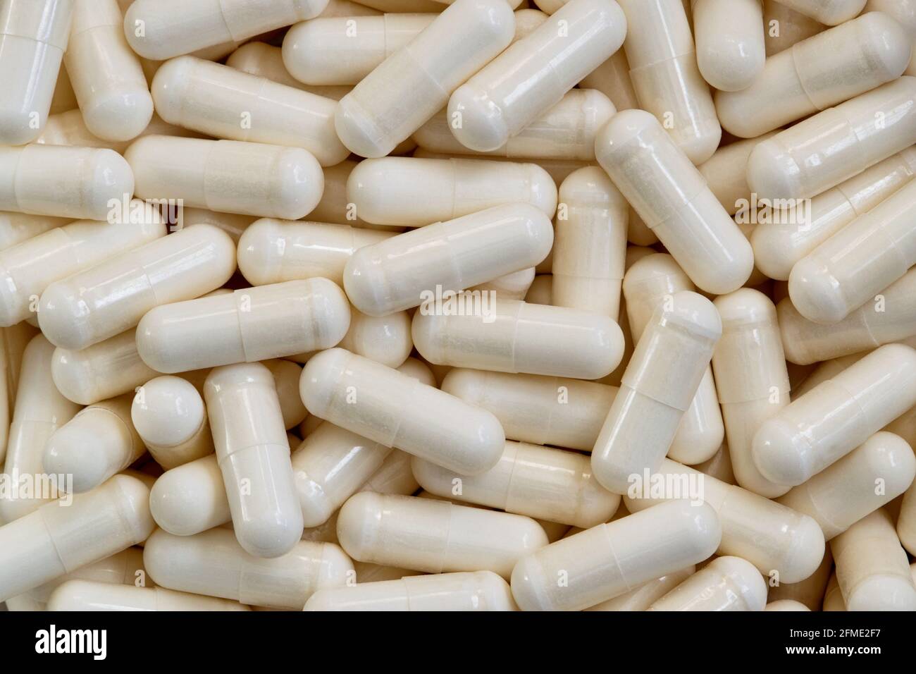 White vitamin supplement capsules scattered loosely, flat lay ...