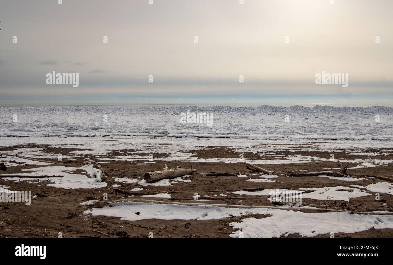 Closeup shot of an open field with ground partly covered by snow and a ...