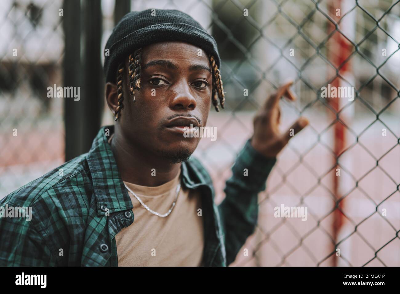 Handsome and stylish Spanish man touching the chain-link fence and ...