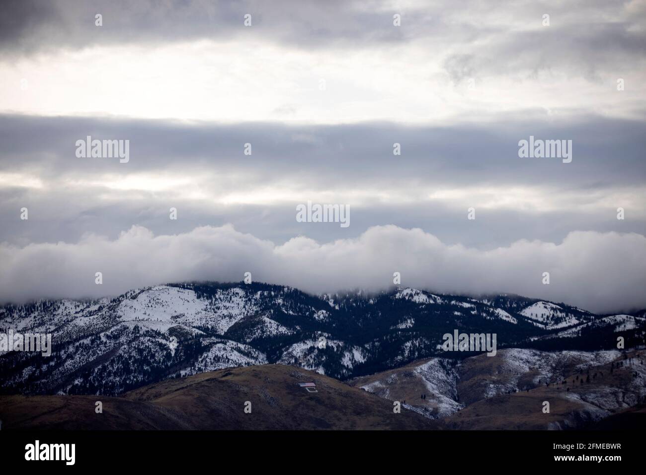 Dark moody clouds hug blue mountains above C hill in Carson City Stock ...