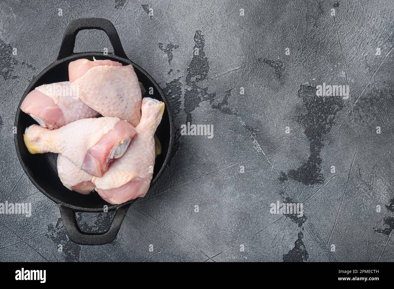 Raw chicken legs set, in frying cast iron pan, on gray stone background ...