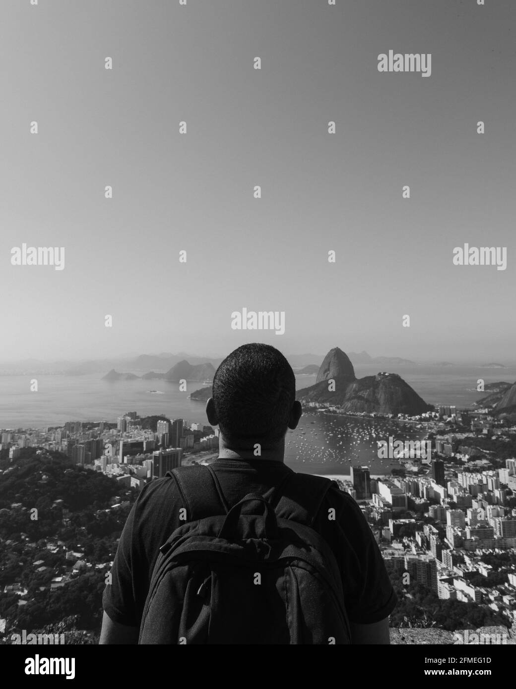 Vertical monochrome shot of a tourist admiring the stunning view of a ...