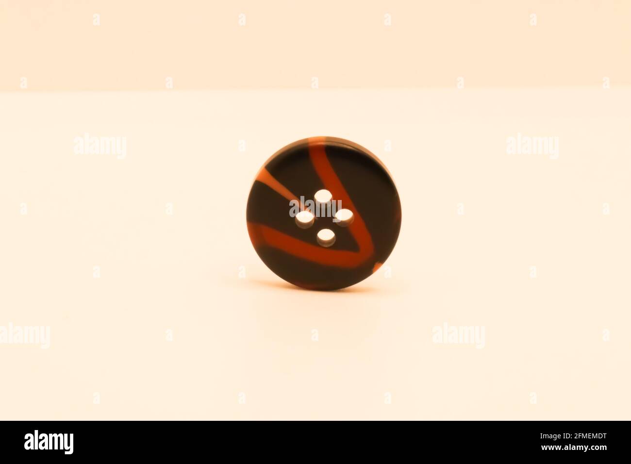 A macro photograph of a single striped four hole clothes button ...