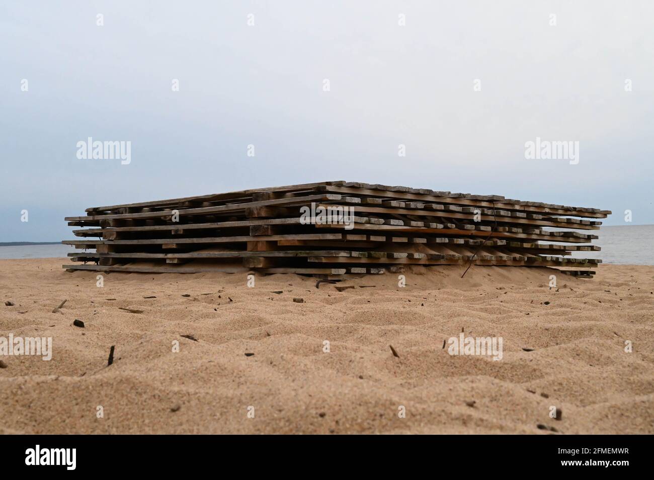 A pile of wooden pallets in the sea sand before sunset Stock Photo - Alamy