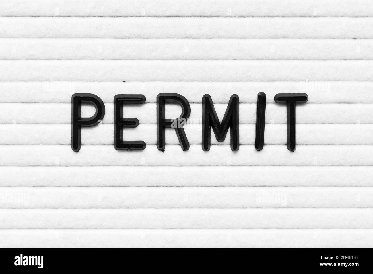 Black alphabet letter in word permit on white felt board background ...