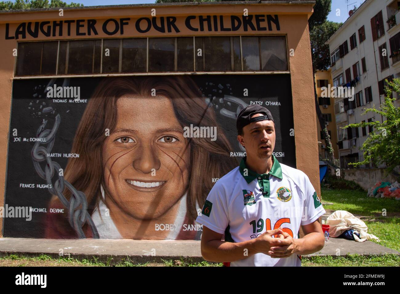 Italian street artist Jorit in front of his mural dedicated to Bobby ...