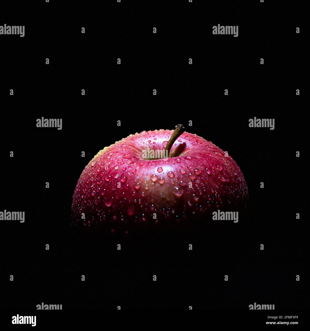 close-up of a red apple, light from above, black background, water ...