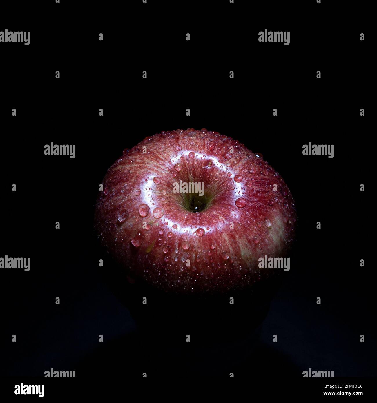close-up of a red apple, light from above, black background, water ...