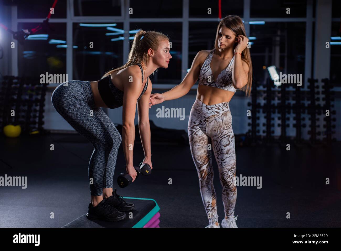 Female fitness instructor conducts personal training. Young attractive woman does deadlift on a ...