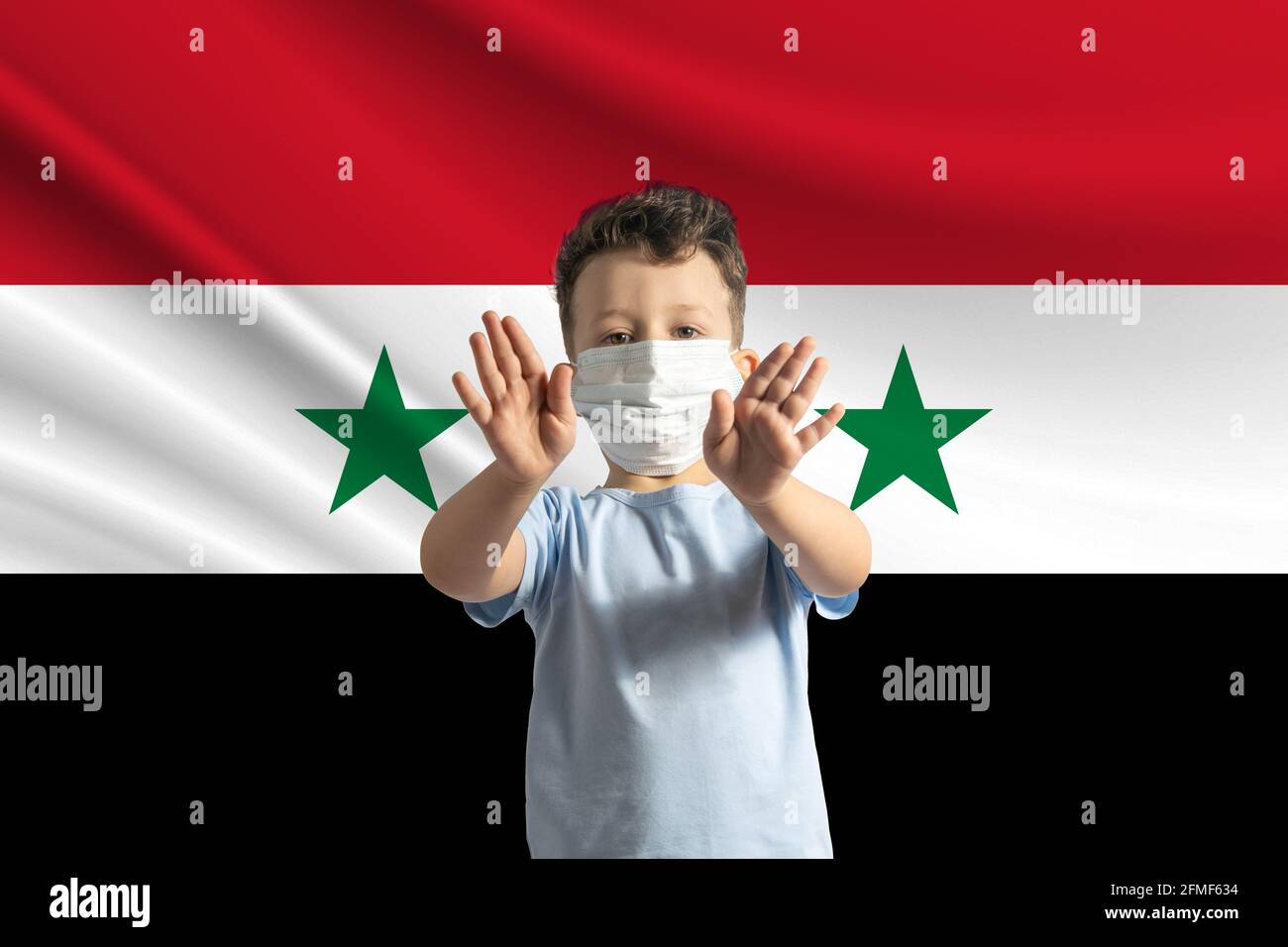 Little white boy in a protective mask on the background of the flag of ...