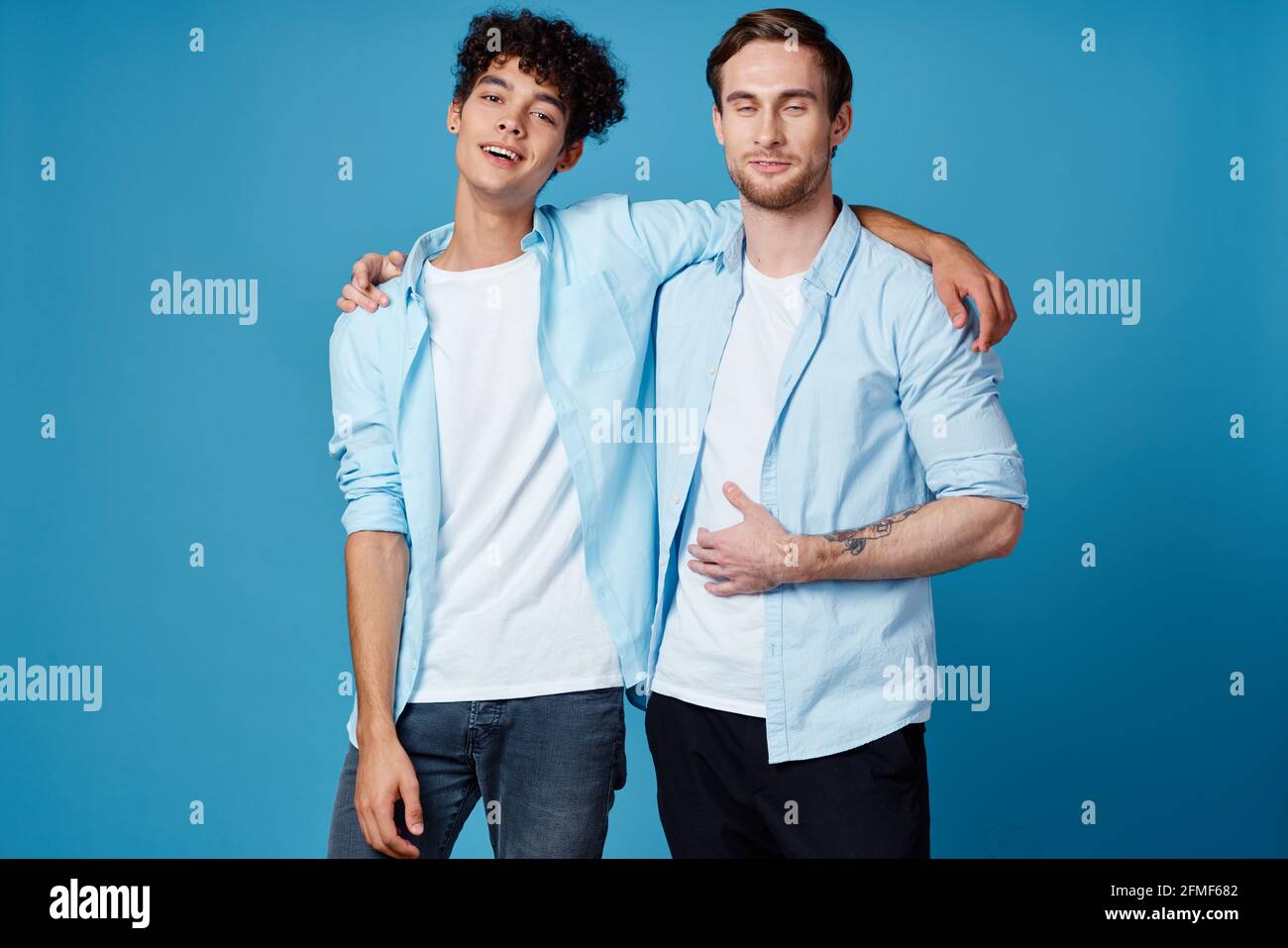 young men in identical shirts hugging on a blue background best friends ...
